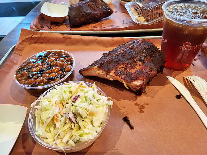 A tray that tells the complete barbecue story—smoky ribs as the protagonist, with beans and slaw providing the essential supporting narrative.
