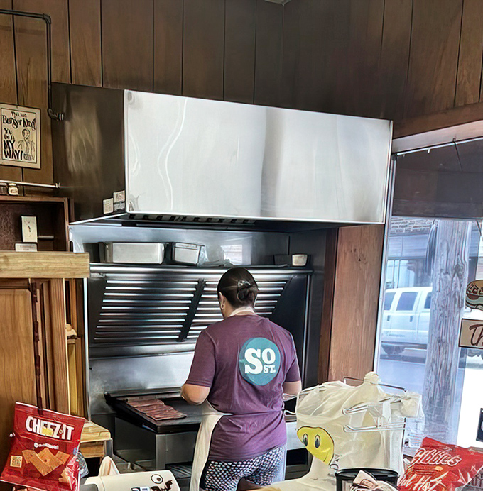 Where sandwich magic happens. The purple shirt and focused stance tell you everything about the care that goes into each order.