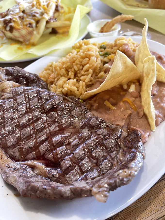 A perfectly grilled steak alongside Spanish rice and refried beans&mdash;the kind of plate that makes you want to tip your hat to the grill master.
