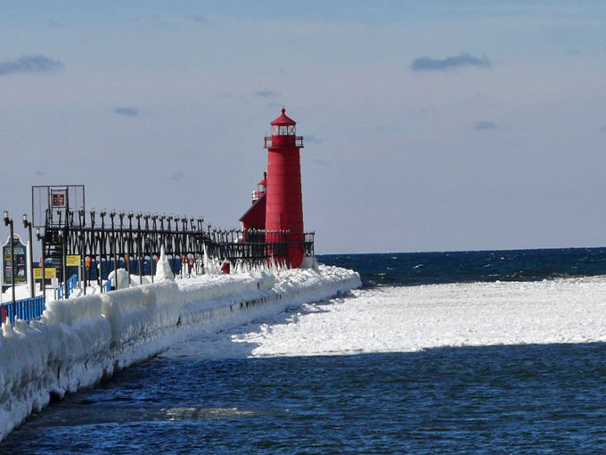 The iconic red lighthouse stands guard at Grand Haven's pier, a splash of color against winter's icy grip on Lake Michigan.