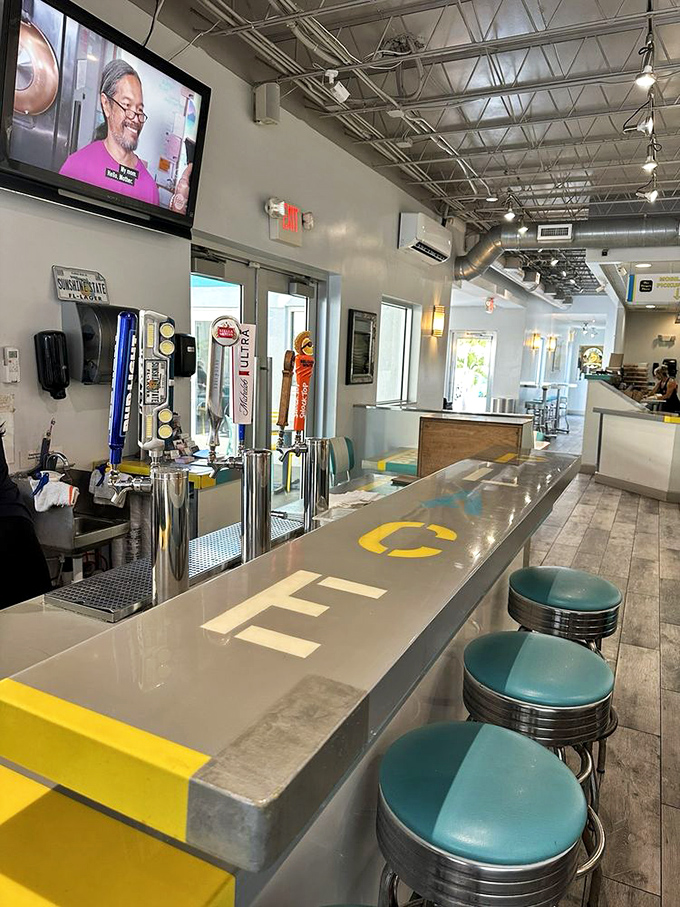 The sleek bar area with turquoise stools offers front-row seats to the culinary action.