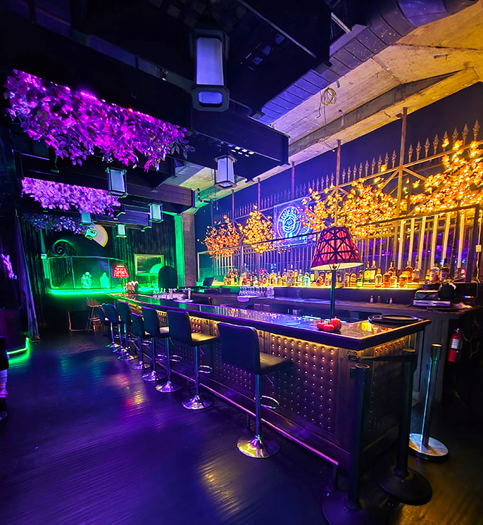 The bar glows with supernatural green light under purple foliage, like an enchanted forest where the potions happen to be premium spirits.