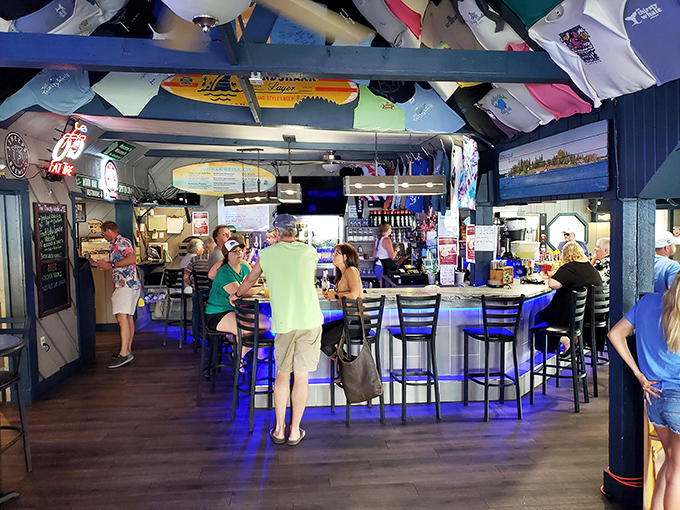 Baseball caps and colorful t-shirts hang from the ceiling like trophies of good times past, creating a museum of summer adventures above happy patrons.