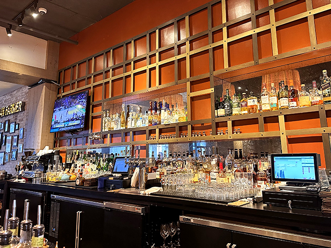 A bar backed by vibrant orange that showcases bottles like trophies&mdash;liquid amber treasures waiting to transform your evening. 