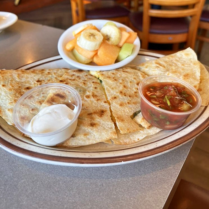 A breakfast quesadilla that bridges cultures and satisfies cravings, served with the holy trinity of toppings: sour cream, salsa, and fresh fruit.