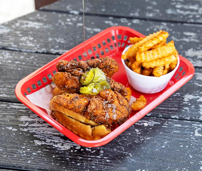 Red plastic baskets cradle the ultimate Southern power couple: hot chicken and seasoned fries. The pickle chips aren't just garnish&mdash;they're essential acid to cut through the richness.