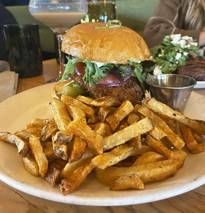 A burger that demands to be photographed before eaten, paired with fries that achieve the golden ratio of crispy exterior to fluffy interior.