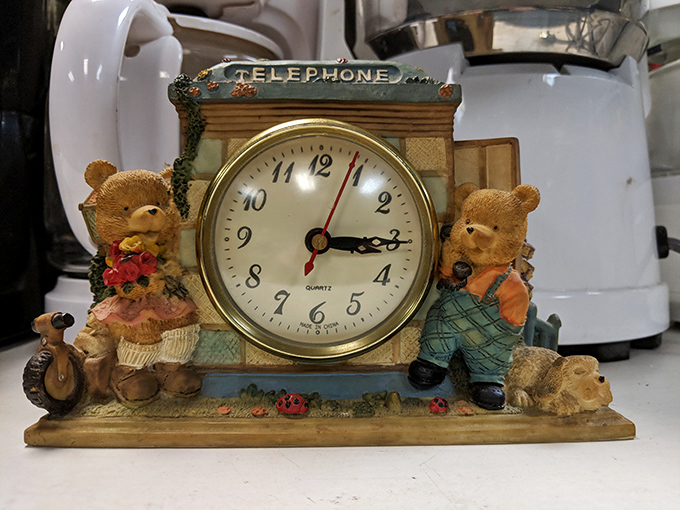 A whimsical telephone-themed clock flanked by teddy bears. Time literally stands still until someone gives this charming timepiece a new home.