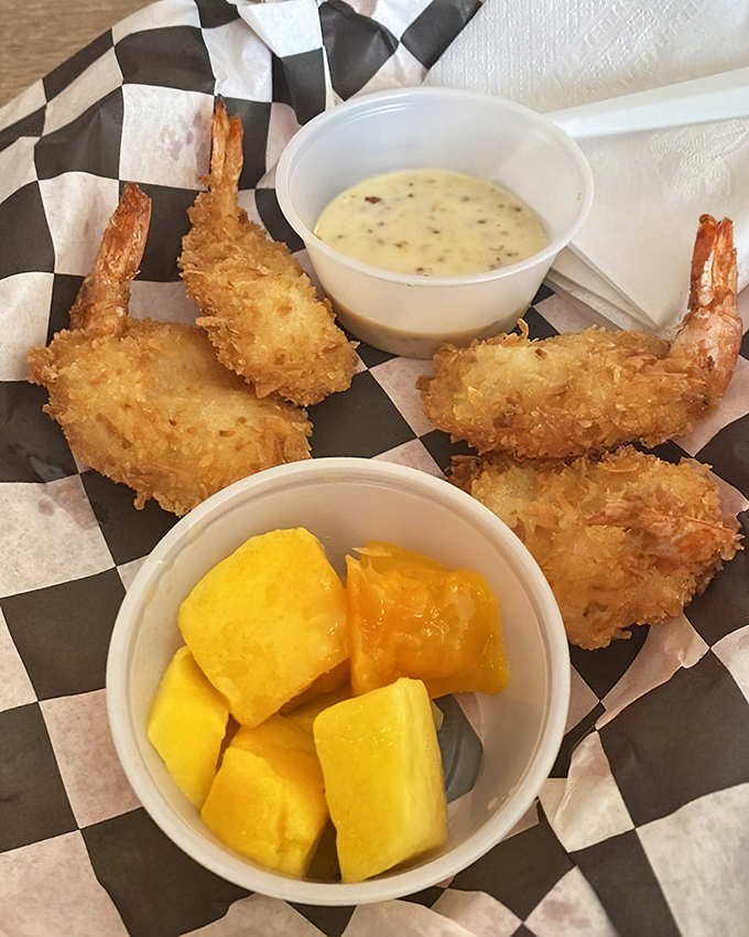 Golden-fried coconut shrimp with dipping sauce and fresh pineapple—a tropical vacation that doesn't require TSA screening.