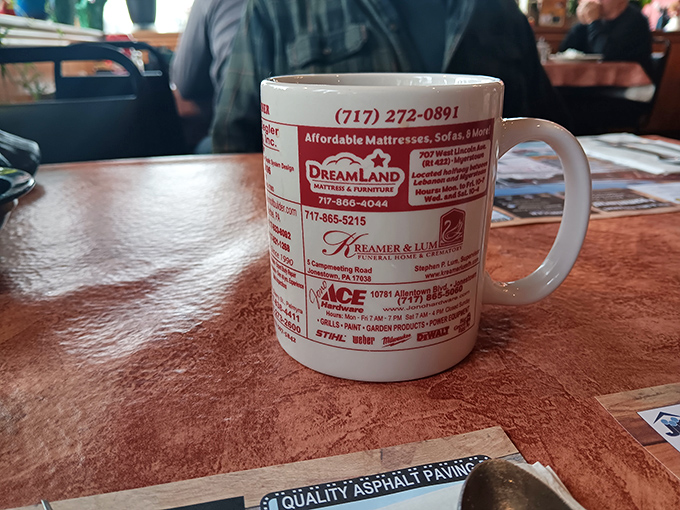 The coffee mug doubles as local yellow pages. In Lebanon, your morning caffeine comes with community connections printed right on the ceramic.