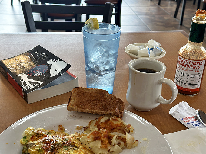 The breakfast trinity: good book, strong coffee, and a half-eaten meal that tells the story of satisfaction. Literary and culinary nourishment together.