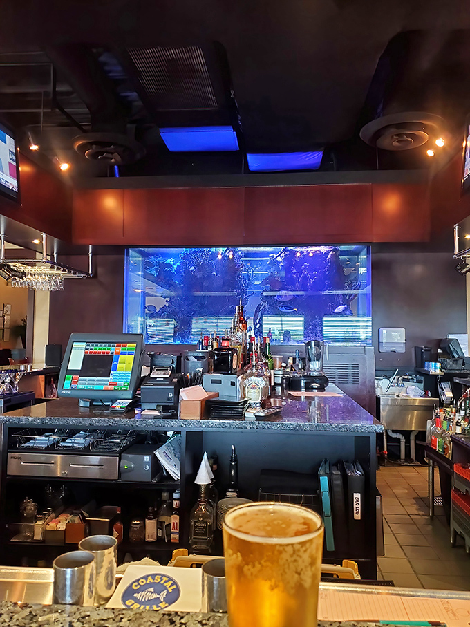 Behind the scenes at the bar, where cocktail magic happens against the hypnotic blue glow of a stunning aquarium.