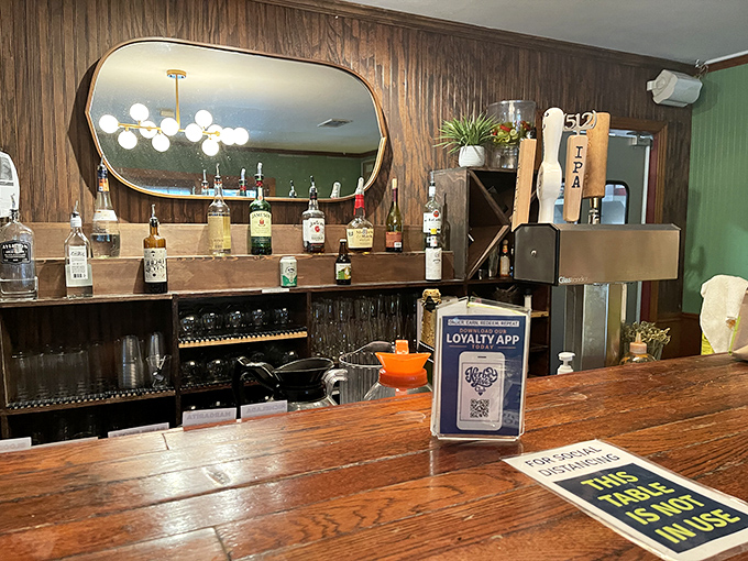 The bar area doesn't just serve drinks – it tells stories through bottles and glasses while that mirror reflects your impending food happiness.