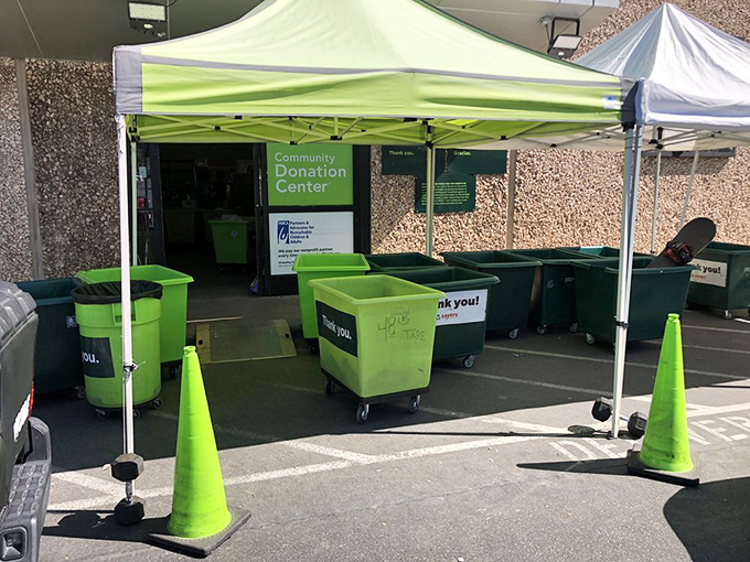 The donation drop-off area buzzes with activity under its green canopy. Every container represents hundreds of items beginning their journey to new homes.