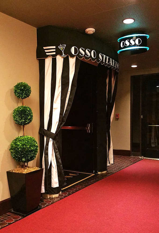 The entrance beckons with theatrical flair&mdash;black and white curtains, a red carpet, and topiary guardians that say, "Yes, this meal will be an event."