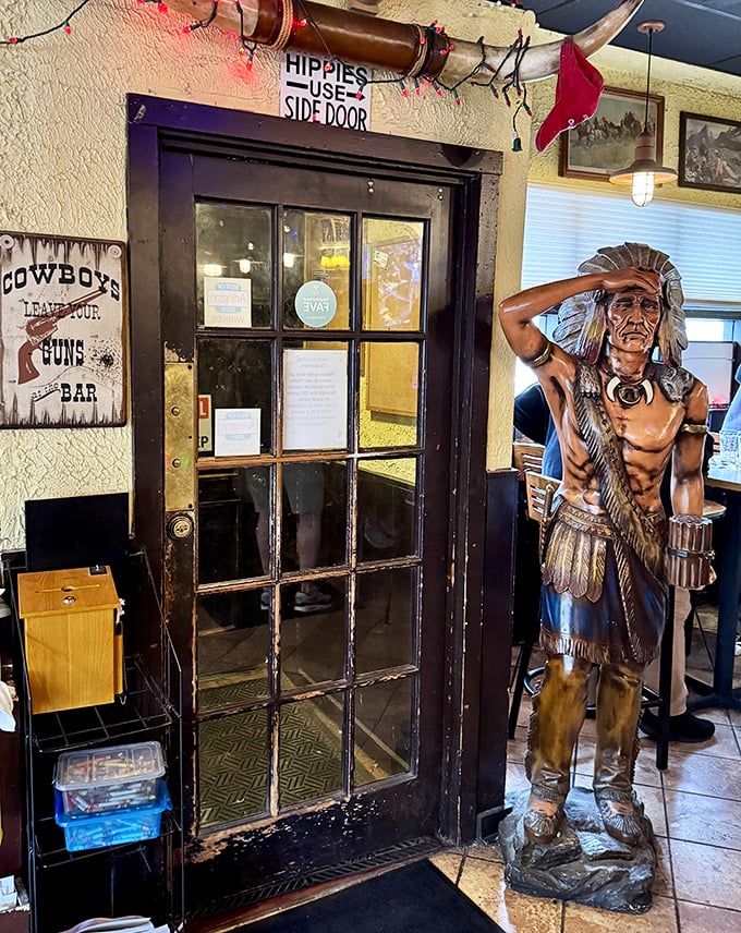Hippies Use Side Door warns the sign above an entrance guarded by a stoic Native American statue. Cowboy humor remains alive and well.