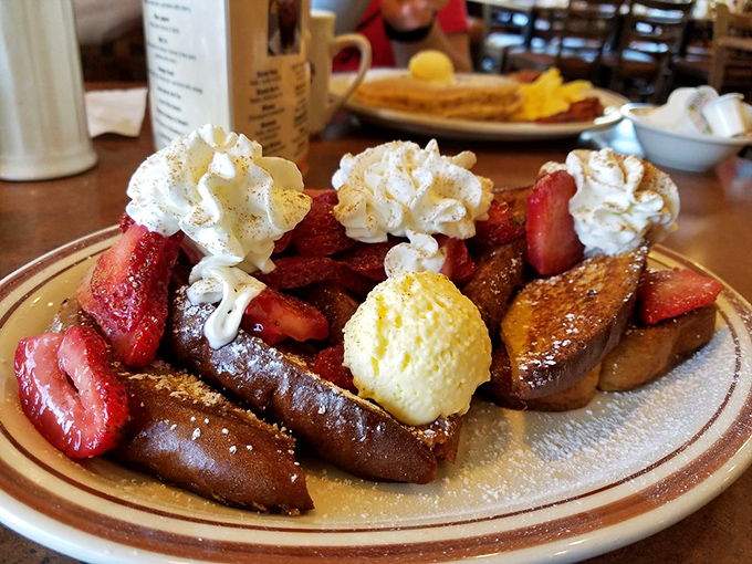 French toast living its best life – crowned with strawberries, whipped cream and surrounded by a supporting cast of sweet decadence.
