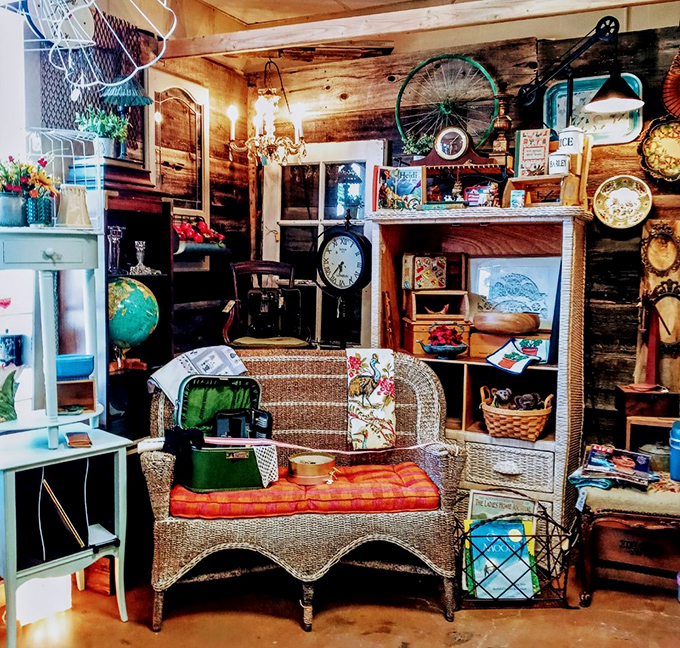 This wicker settee surrounded by vintage curiosities is begging to be the centerpiece of someone's screened porch or reading nook.