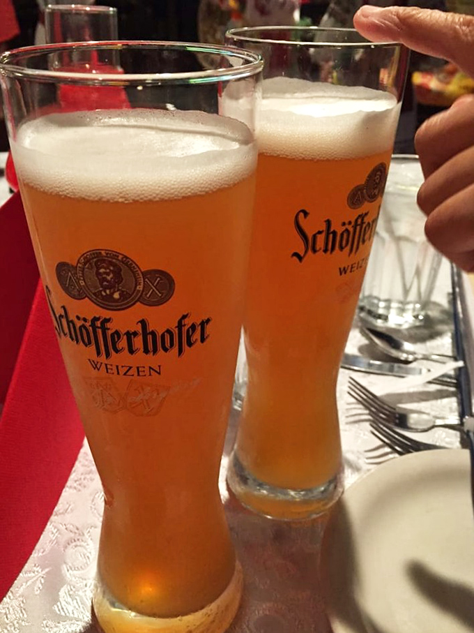 Two Schöfferhofer Weizen beers standing tall and proud. Their cloudy amber glow and frothy tops are practically a vacation in a glass.