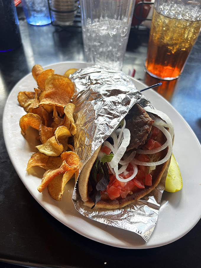 This isn't just a gyro – it's an architectural marvel wrapped in foil, bursting with fresh veggies and meat, escorted by golden potato chips.