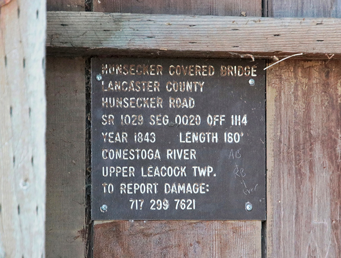 A humble plaque reveals the bridge's impressive statistics: built in 1843, spanning 180 feet across the Conestoga River.