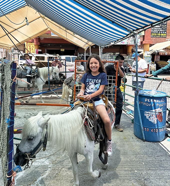 Childhood joy captured in motion&mdash;this pony ride brings the county fair experience to an urban marketplace, complete with blue-jeaned smiles.