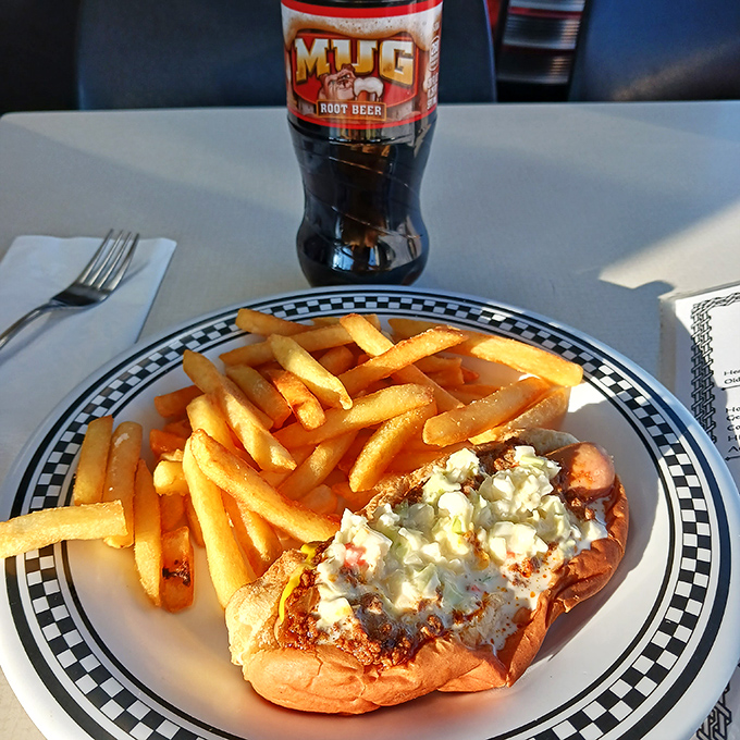 The holy trinity of diner perfection: a loaded dog, golden fries, and an ice-cold Mug Root Beer &ndash; America's comfort food trifecta in its natural habitat.