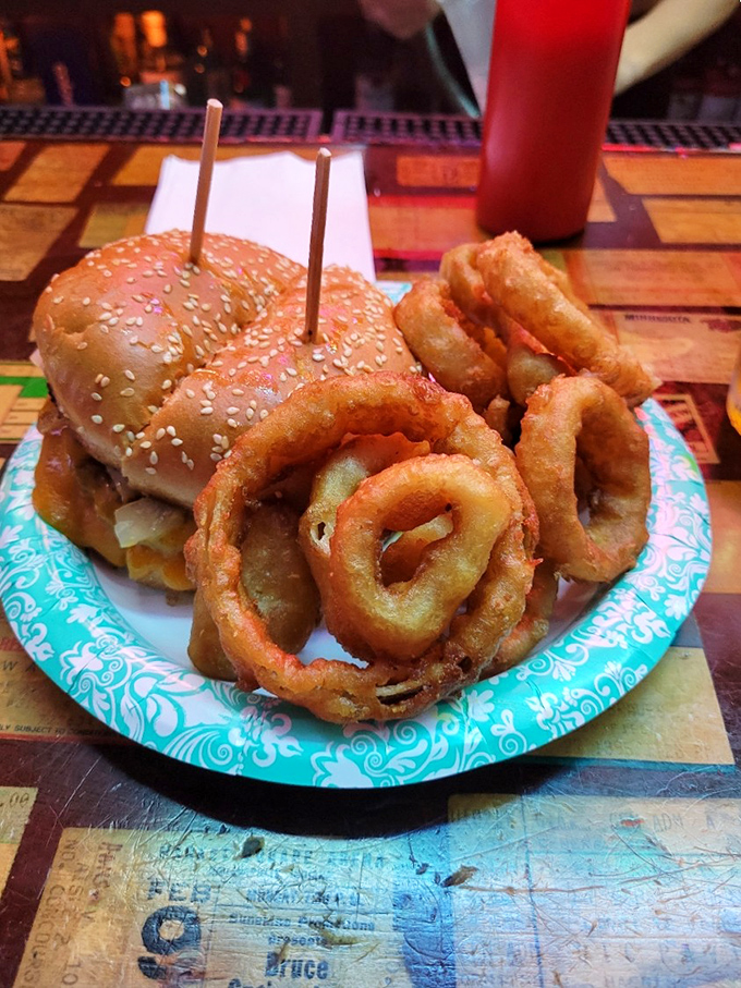 A proper burger deserves proper company - crisp onion rings and a hearty sandwich held together with wooden picks like tiny structural supports.