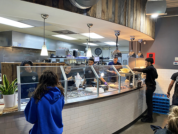 Behind glass barriers, culinary magic happens as the kitchen team orchestrates the breakfast symphony that has made Atlanta Breakfast Club legendary throughout Georgia.