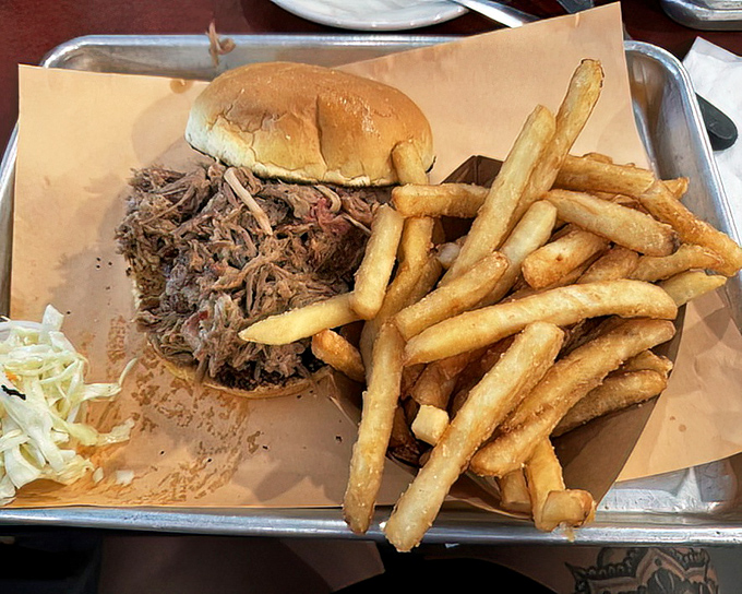 The pulled pork sandwich – where smoke-kissed meat meets pillowy bun in a relationship your taste buds will want to third-wheel.
