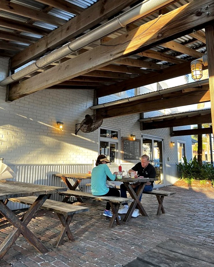 Sunshine filtering through wooden beams creates the perfect ambiance. This outdoor seating area practically demands you linger over lunch.