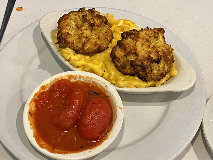 Crab cakes perched atop mac and cheese with stewed tomatoes on the side—a Delaware twist on comfort food that hits all the right notes.