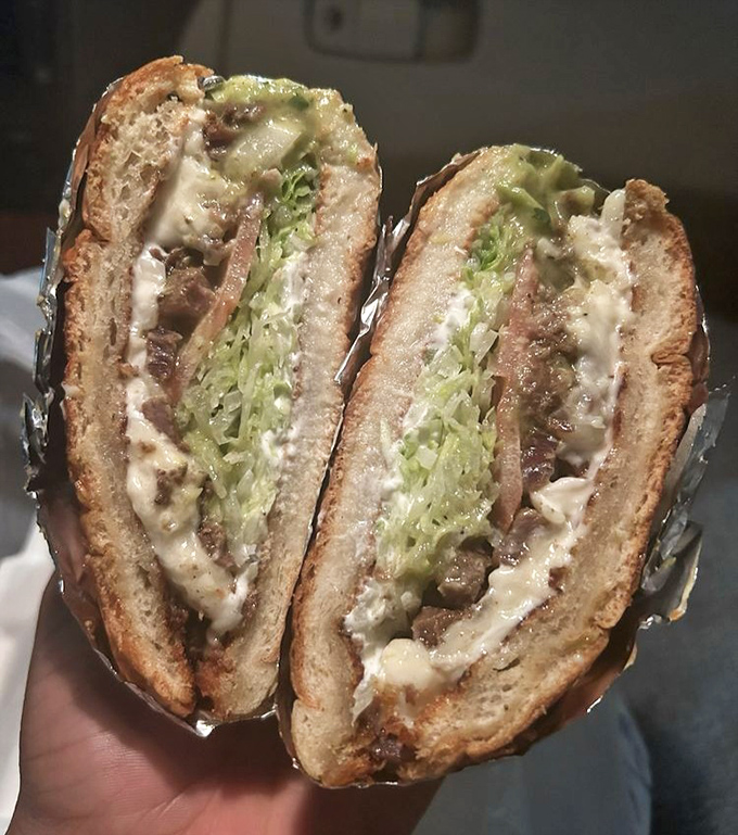 This torta cross-section reveals layers of perfectly seasoned meat, fresh vegetables, and creamy avocado in crusty bread. 