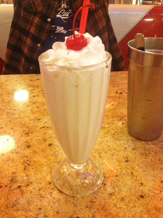 The classic vanilla shake arrives crowned with whipped cream and a cherry. In milkshake language, this is practically formal evening wear.