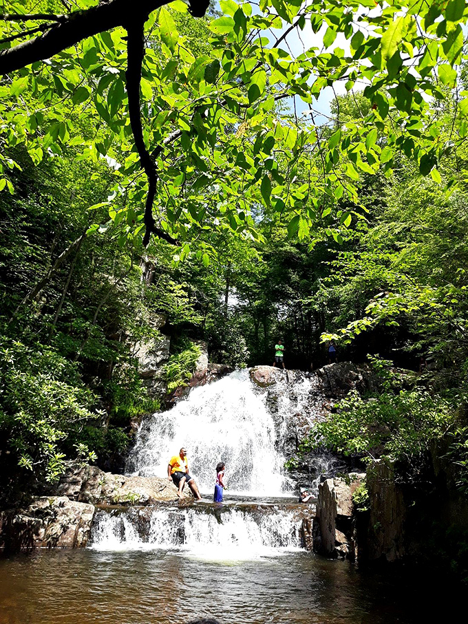 Visitors cool off in the refreshing waters beneath cascading falls that make summer heat completely forgettable.