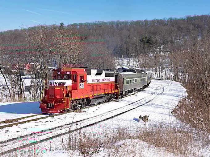 Winter transforms the journey into a Currier and Ives print come to life. The red locomotive provides the only splash of warmth in this snow-blanketed landscape.