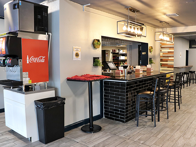 The bar area balances form and function with sleek black tiles and warm wood accents. It's where strangers become friends and friends become regulars.