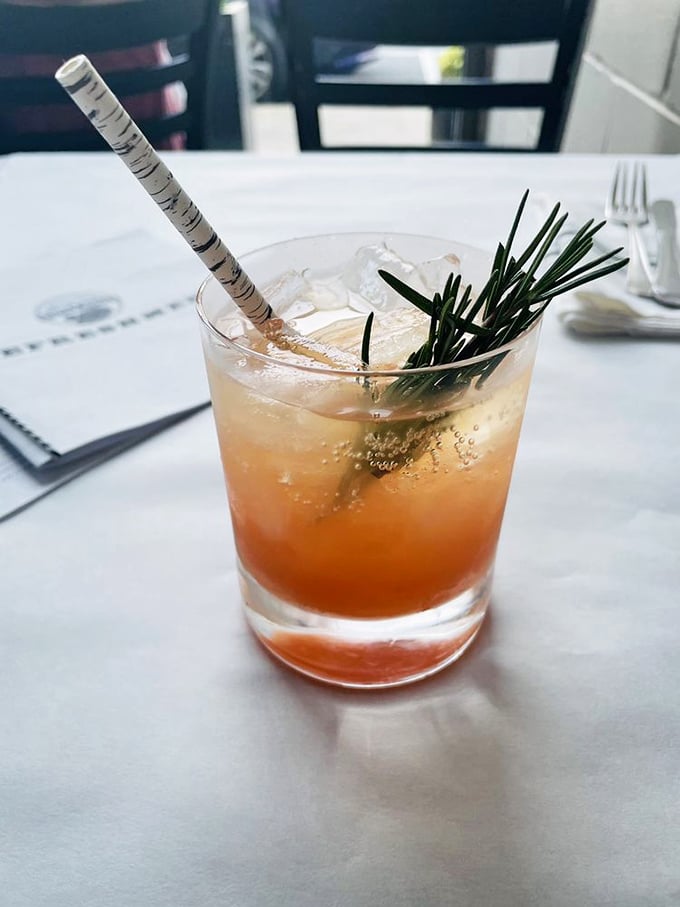 A craft cocktail garnished with rosemary &ndash; like a beach vacation in a glass, sophisticated yet utterly relaxing.