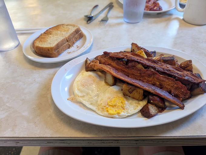 The breakfast trinity: perfectly cooked eggs, crispy bacon, and potatoes that have been transformed into golden cubes of morning joy.