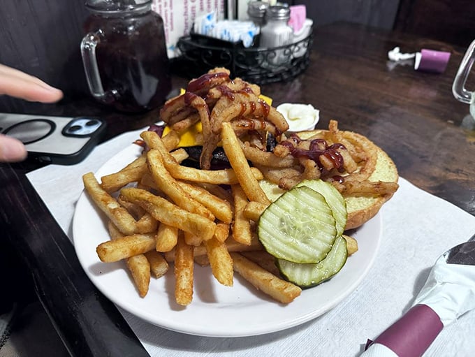 A burger that demands a two-handed commitment, surrounded by fries that look hand-cut by someone who cares about your happiness. The pickle slices add a necessary tang.