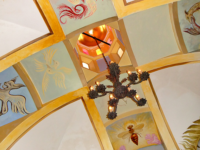 Look up to discover a celestial ceiling where painted insects and mythical creatures float above, watching visitors with the same curiosity we watch them.