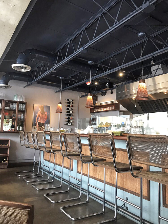 The counter seating offers front-row tickets to the culinary show, with woven chairs that invite you to settle in for another cortadito.