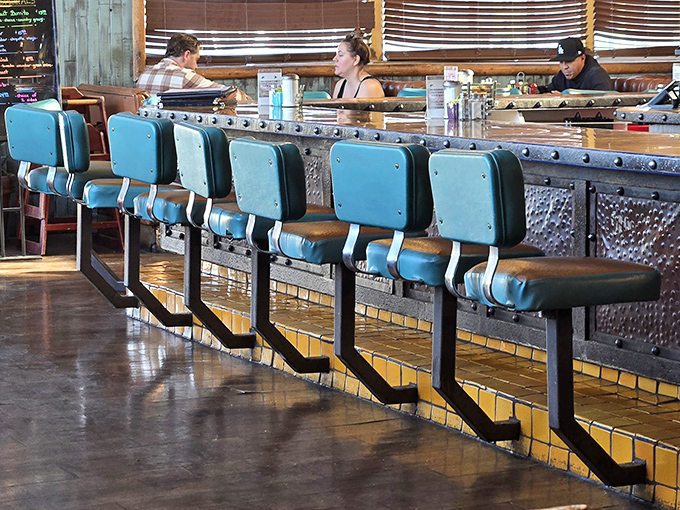 Counter seating where solo diners become temporary neighbors and the blue chairs invite you to stay for just one more coffee.