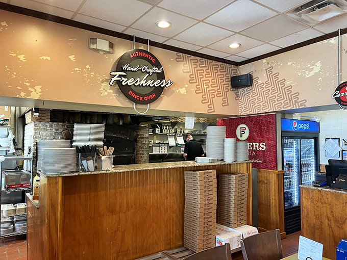 Behind this counter, pizza artisans work their magic. The "Hand-Crafted Freshness" sign isn't just decoration&mdash;it's a promise.