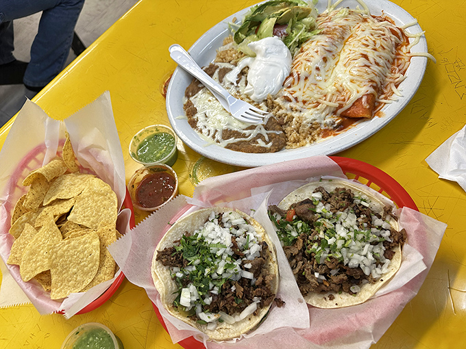 A spread worthy of a Mexican food enthusiast's dream &ndash; enchiladas, tacos, and chips creating the holy trinity of comfort food on one sunny yellow table.