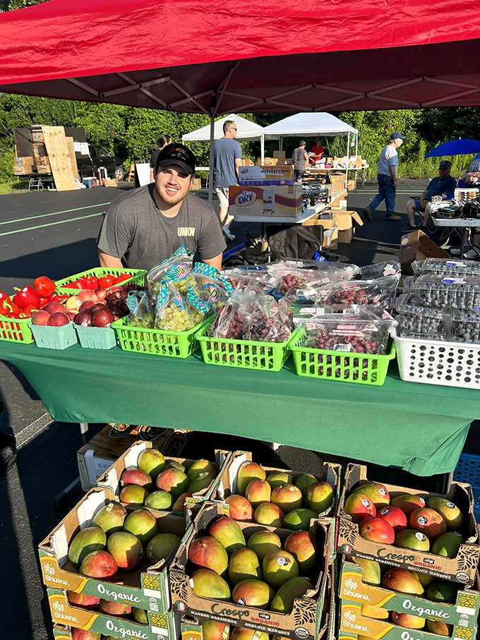 Farm-fresh produce mingles with flea market treasures, proving that sustenance comes in many forms. Those mangoes look almost as tempting as that vintage lamp.