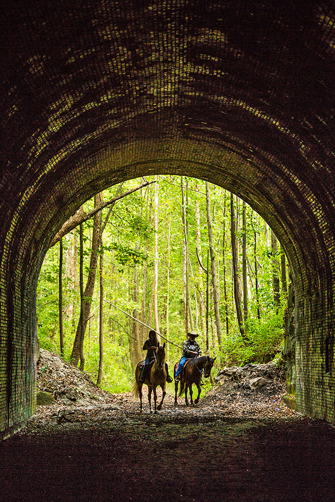 Horseback riders emerge from the tunnel's darkness, creating a scene that could have been plucked straight from another century.