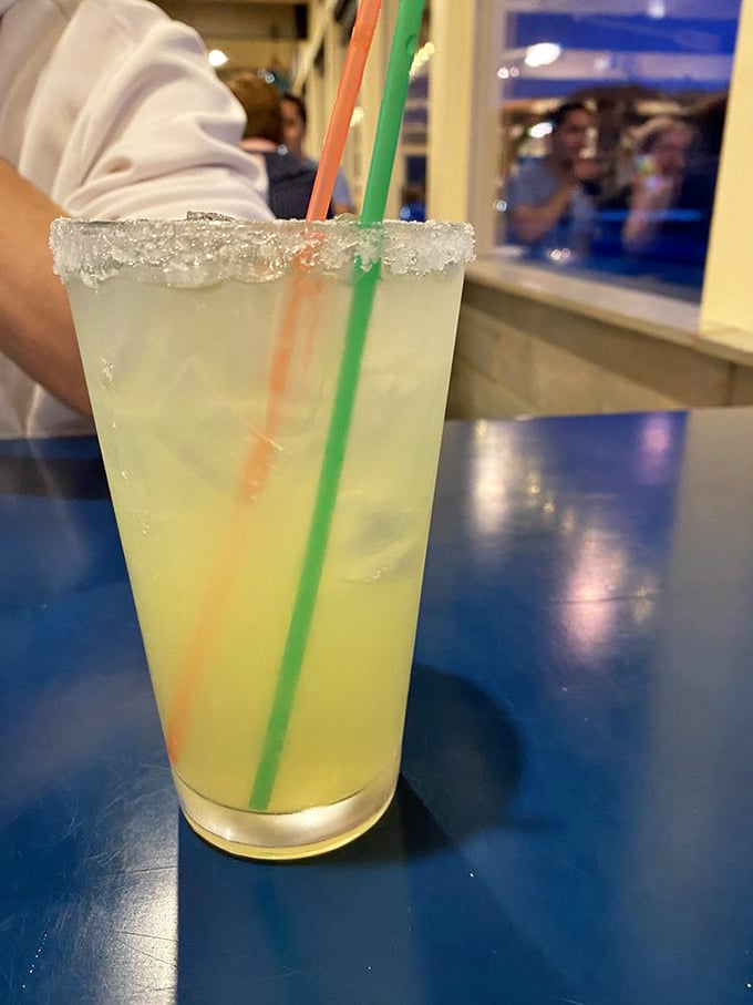 A salt-rimmed margarita with colorful straws stands ready for sipping while watching waves crash. Coastal drinking at its finest&mdash;refreshing, bright, and vacation-mandatory.