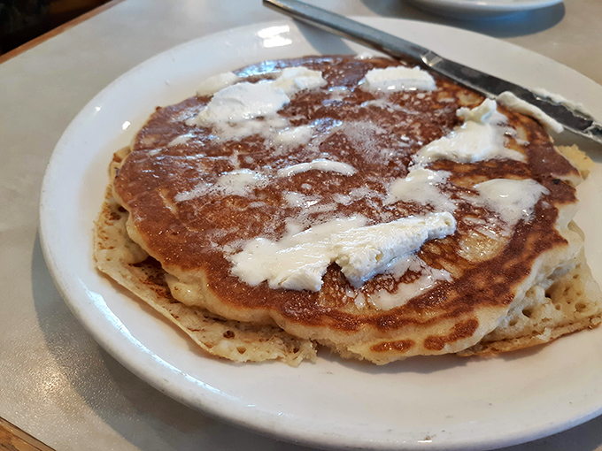 Pancakes wearing their butter like a crown, with a golden-brown complexion that speaks of griddle mastery and morning promise.