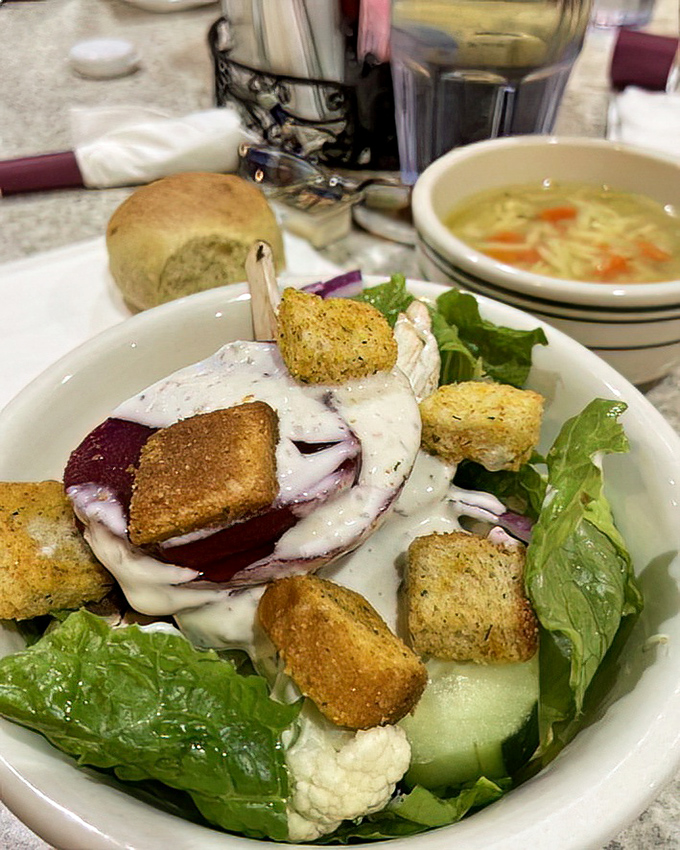 A garden-fresh salad adorned with crunchy croutons and ribbons of creamy dressing—proof that even the simplest starters receive careful attention here.